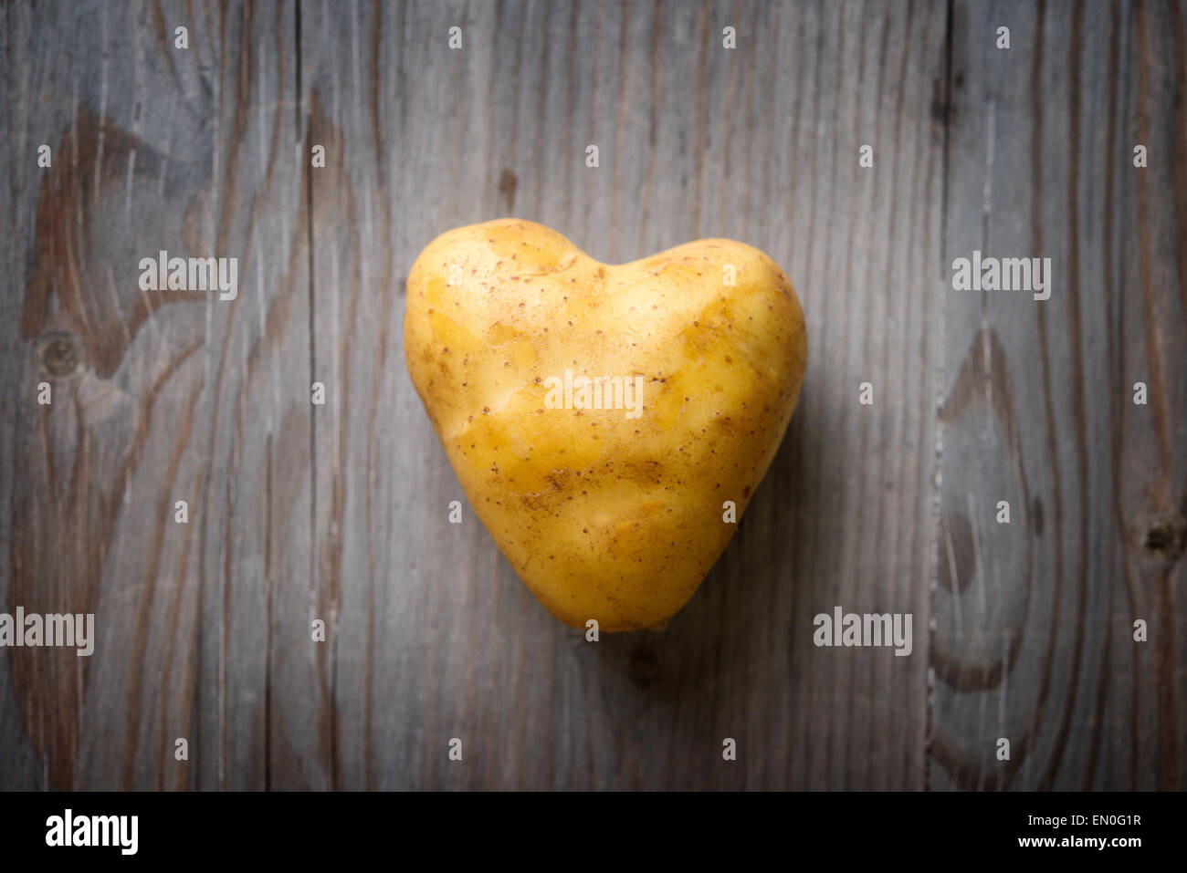 Heart shaped golden potato spud on Wooden Table Background, Concept and ...