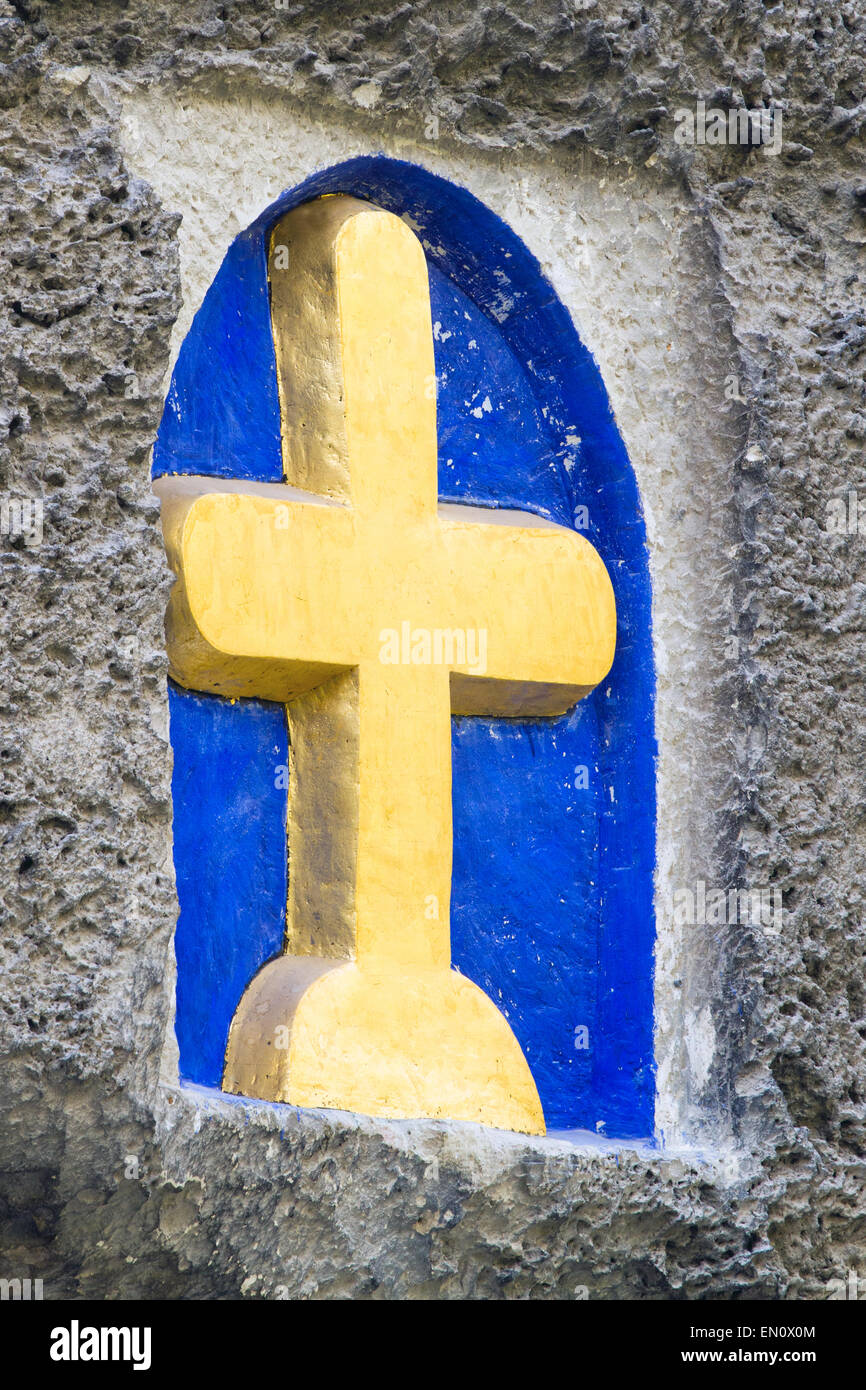 Yellow cross on stone wall. Faith symbol Stock Photo - Alamy