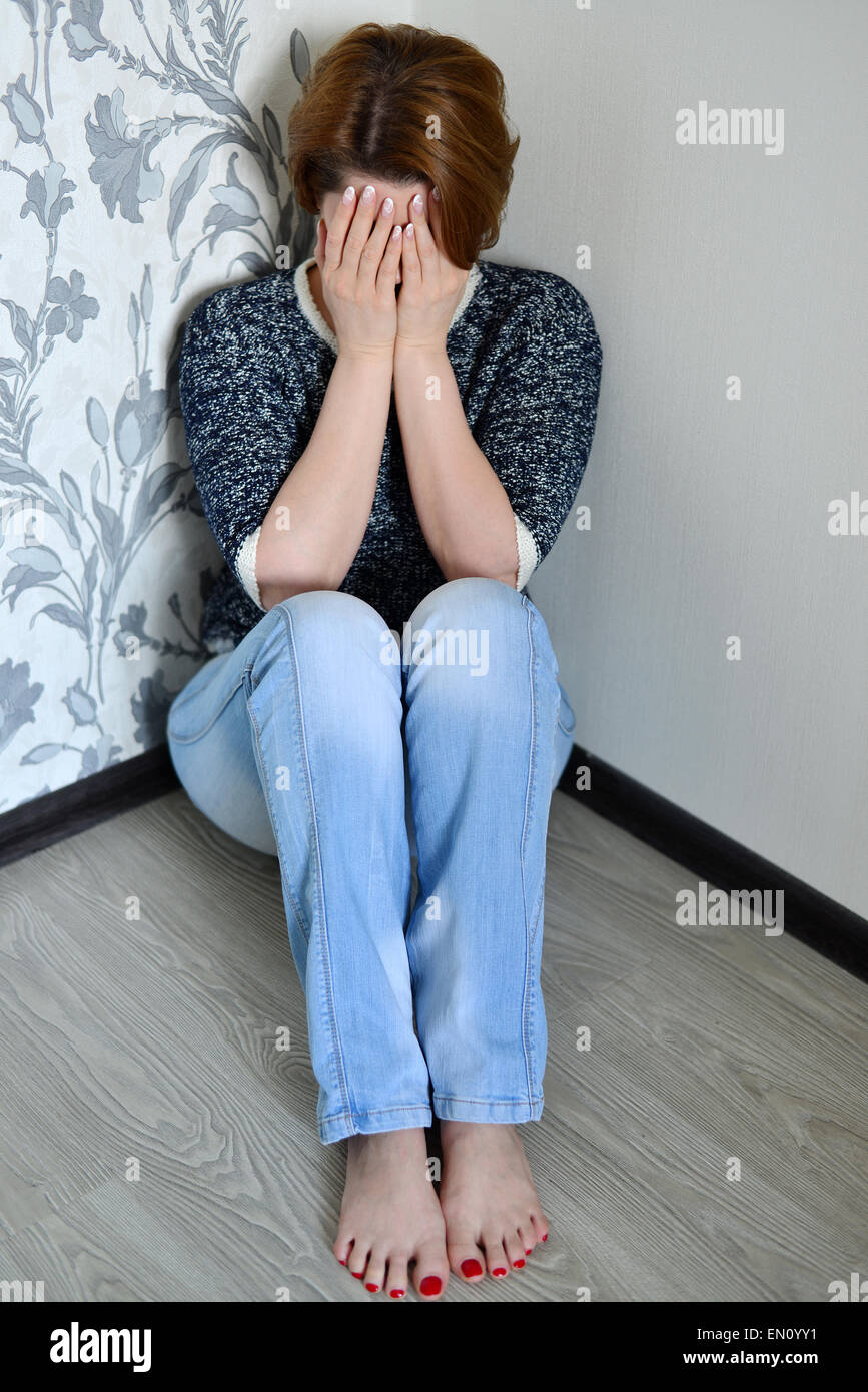 Woman with depression sitting in the corner of the room Stock Photo - Alamy