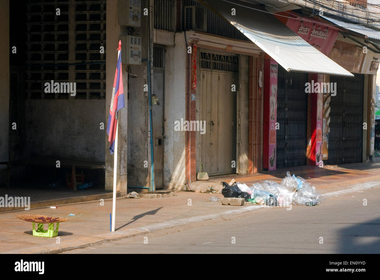 A Cambodian flag is displayed near a pile of garbage on a deserted city ...