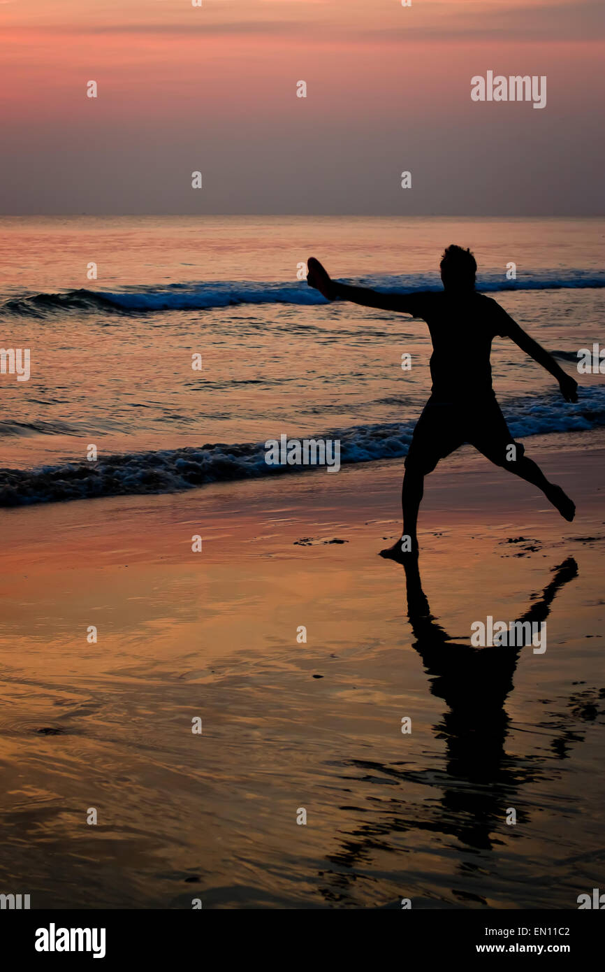 Man playing frisbee on the beach at sunset Stock Photo - Alamy