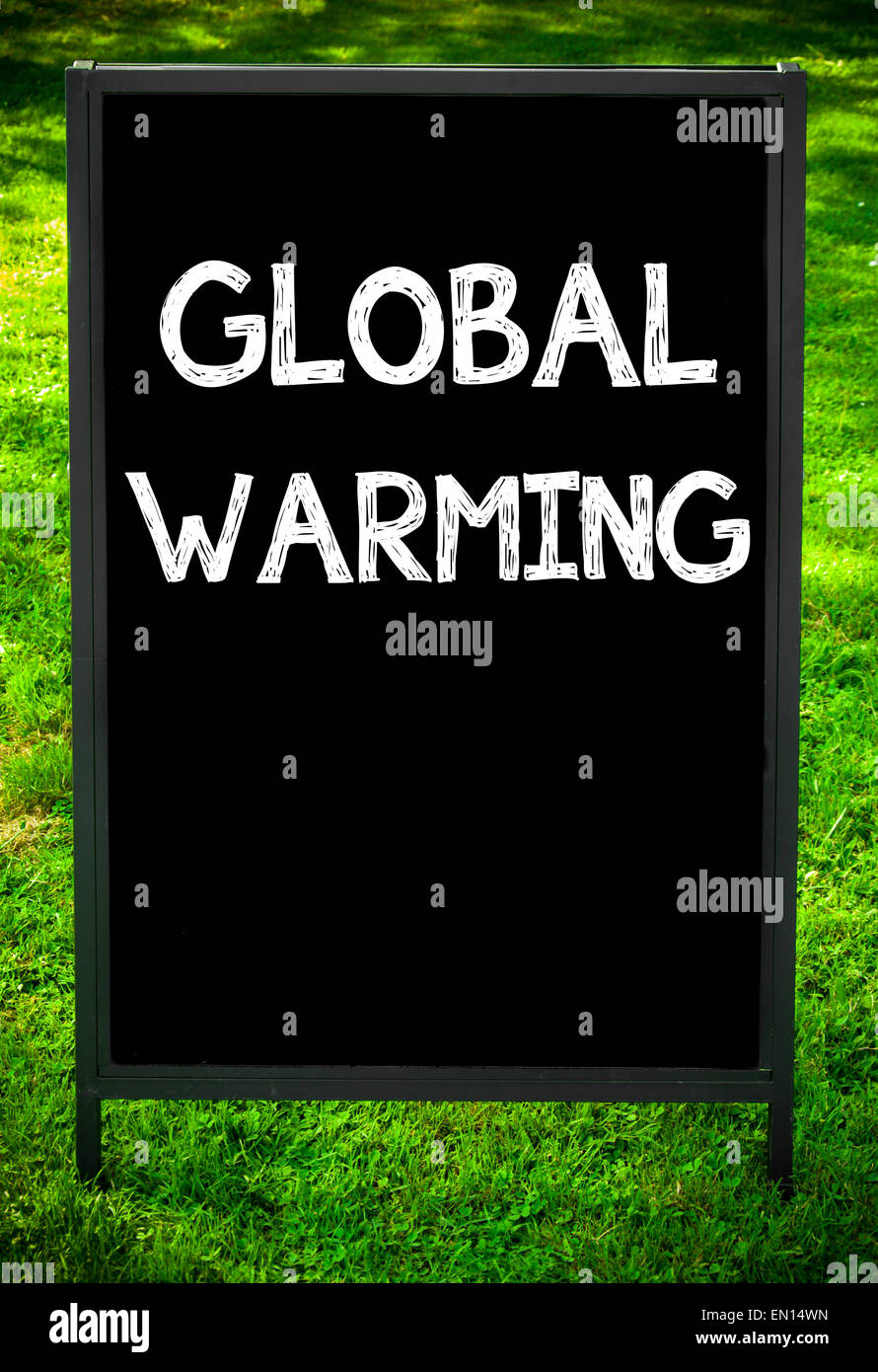 GLOBAL WARMING message on sidewalk blackboard sign against green grass ...