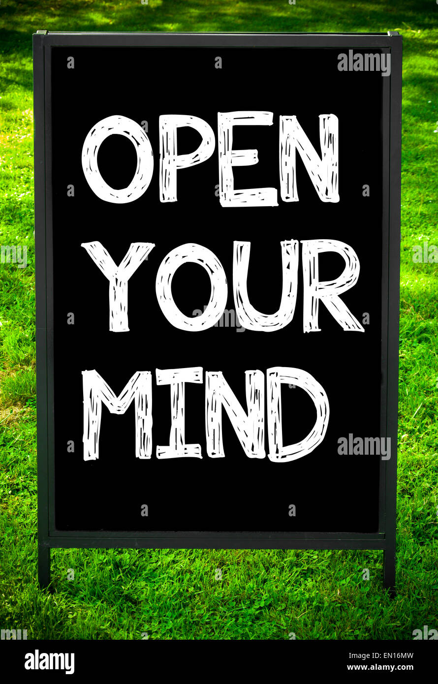 OPEN YOUR MIND message on sidewalk blackboard sign against green grass ...