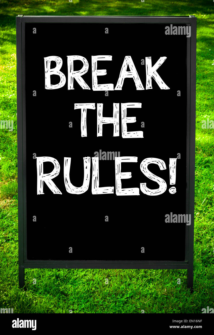 BREAK THE RULES! message on sidewalk blackboard sign against green ...
