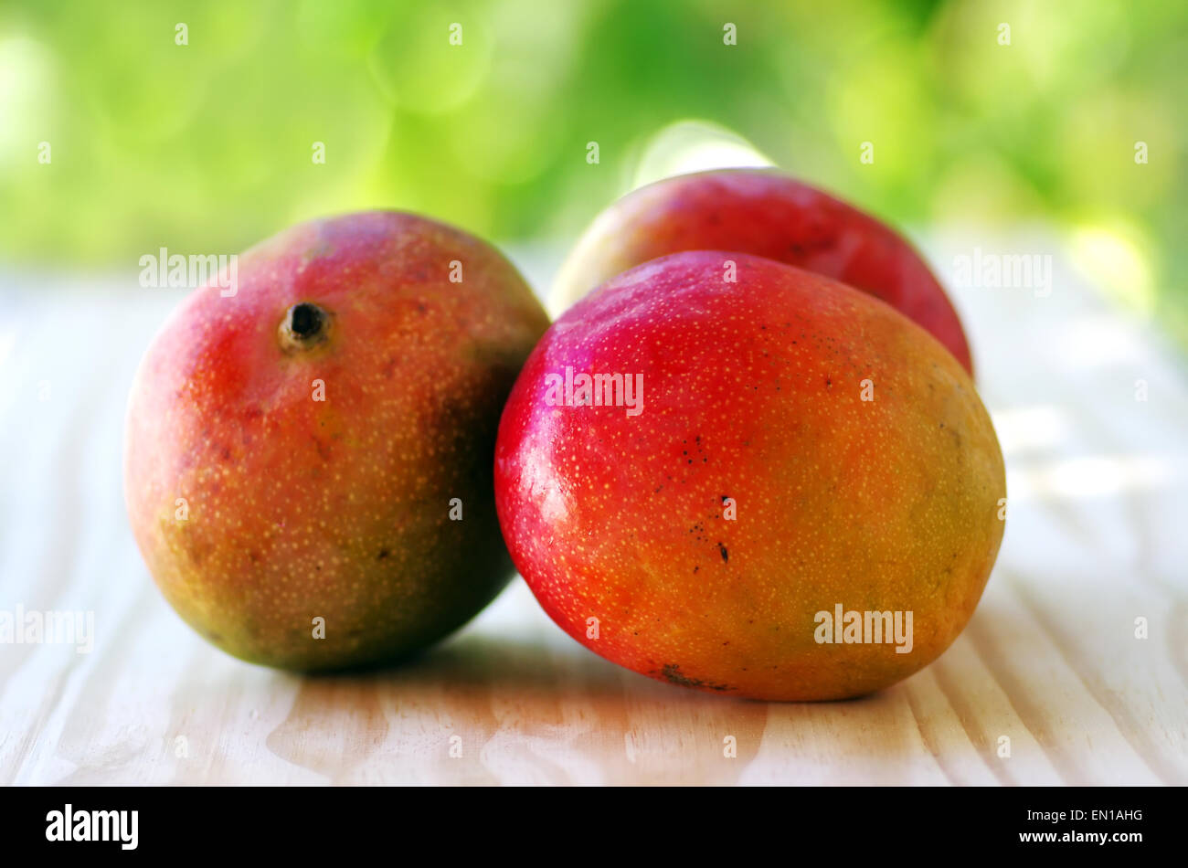 three mangoes fruits on table Stock Photo - Alamy