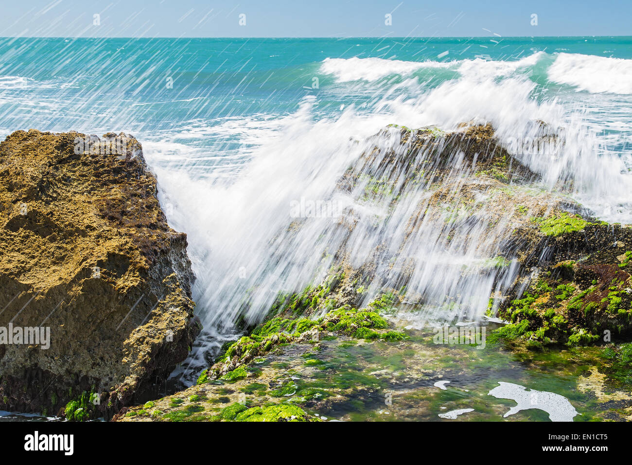 Turquoise rolling wave slamming on the rocks of the coastline Stock ...