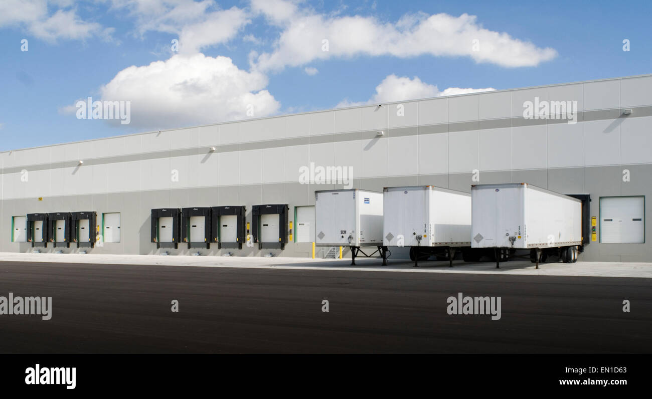 Logistics building, trucks & containers being loaded Stock Photo - Alamy