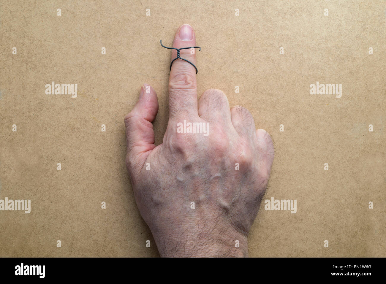 Wire on index finger of an elderly man. Wooden background Stock Photo ...