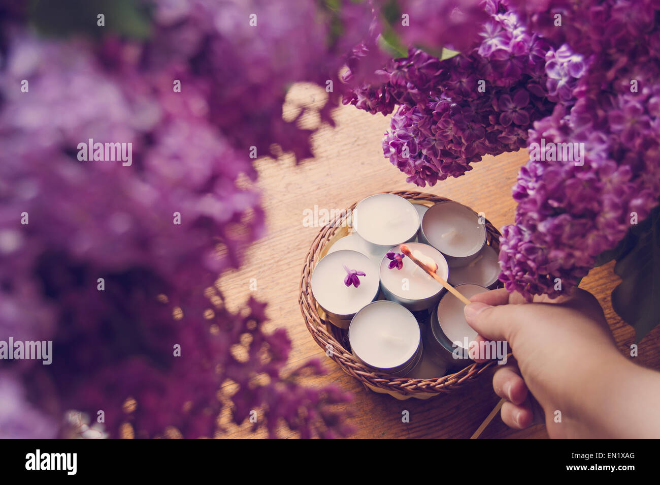 Hand lighting small white candles in a basket surrounded by beautiful ...