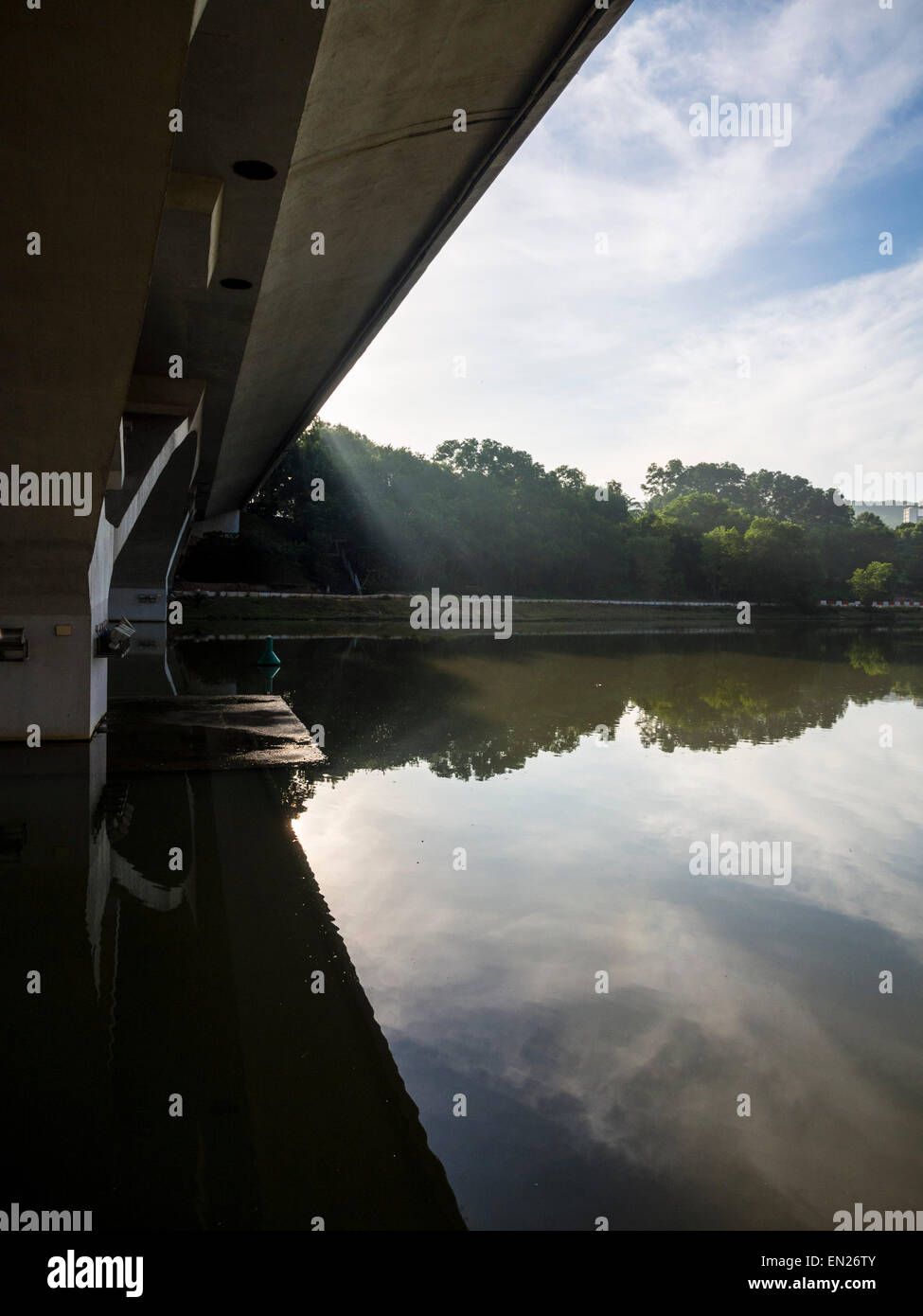 Reflections of trees and clouds on a lake, viewed from under a bridge ...