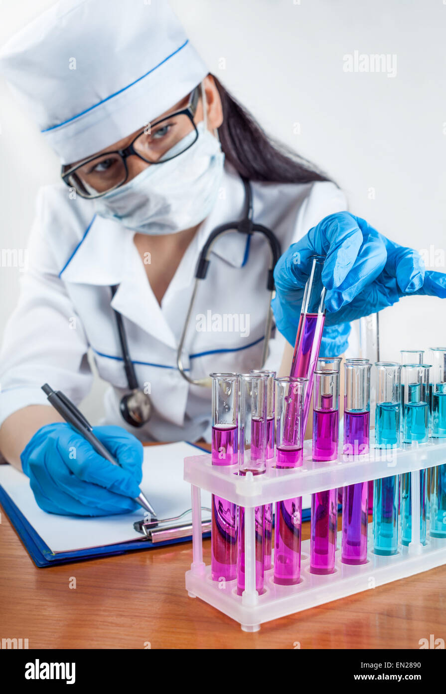 laboratorian examines the contents of the test tubes closeup on a light ...