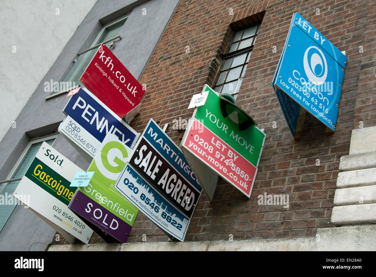 cluster of estate agents signs, for sales and lettings, on a building ...