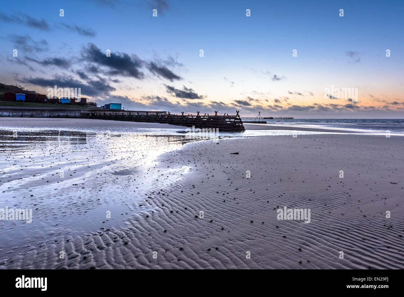 An early morning scene on the beach at low tide with the sun rising on ...