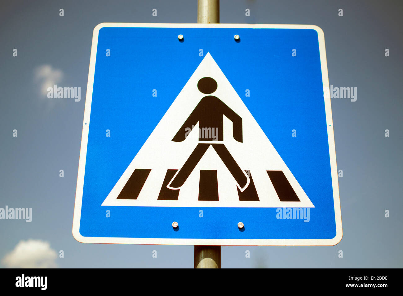 Blue pedestrian crossing sign against blue sky Stock Photo - Alamy