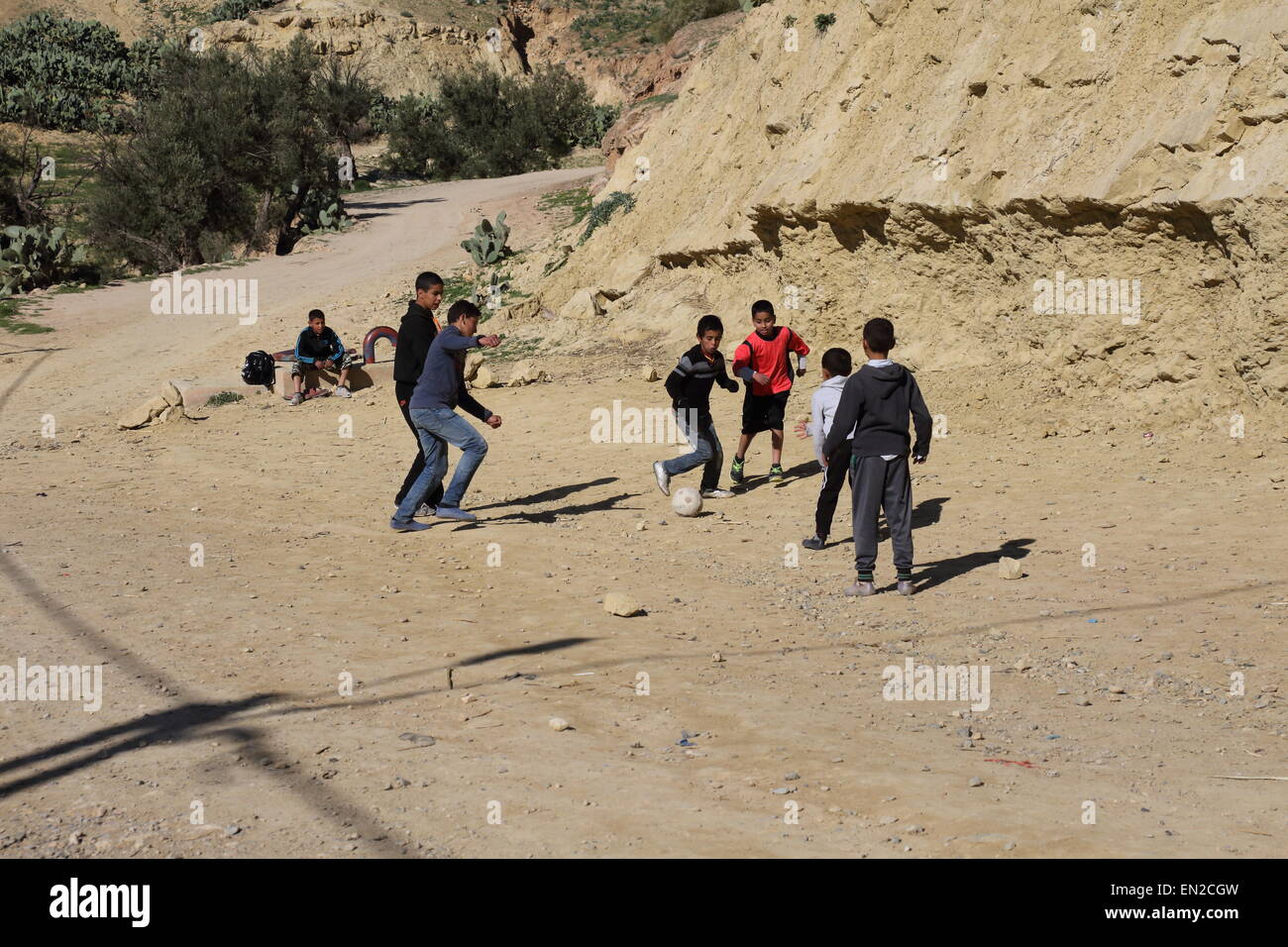 Berber children playing football in the sandy landscape of Sidi Hassain ...