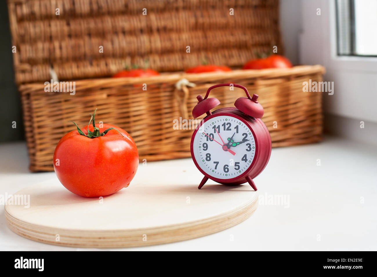 One tomato and red clock on retro box background Stock Photo - Alamy