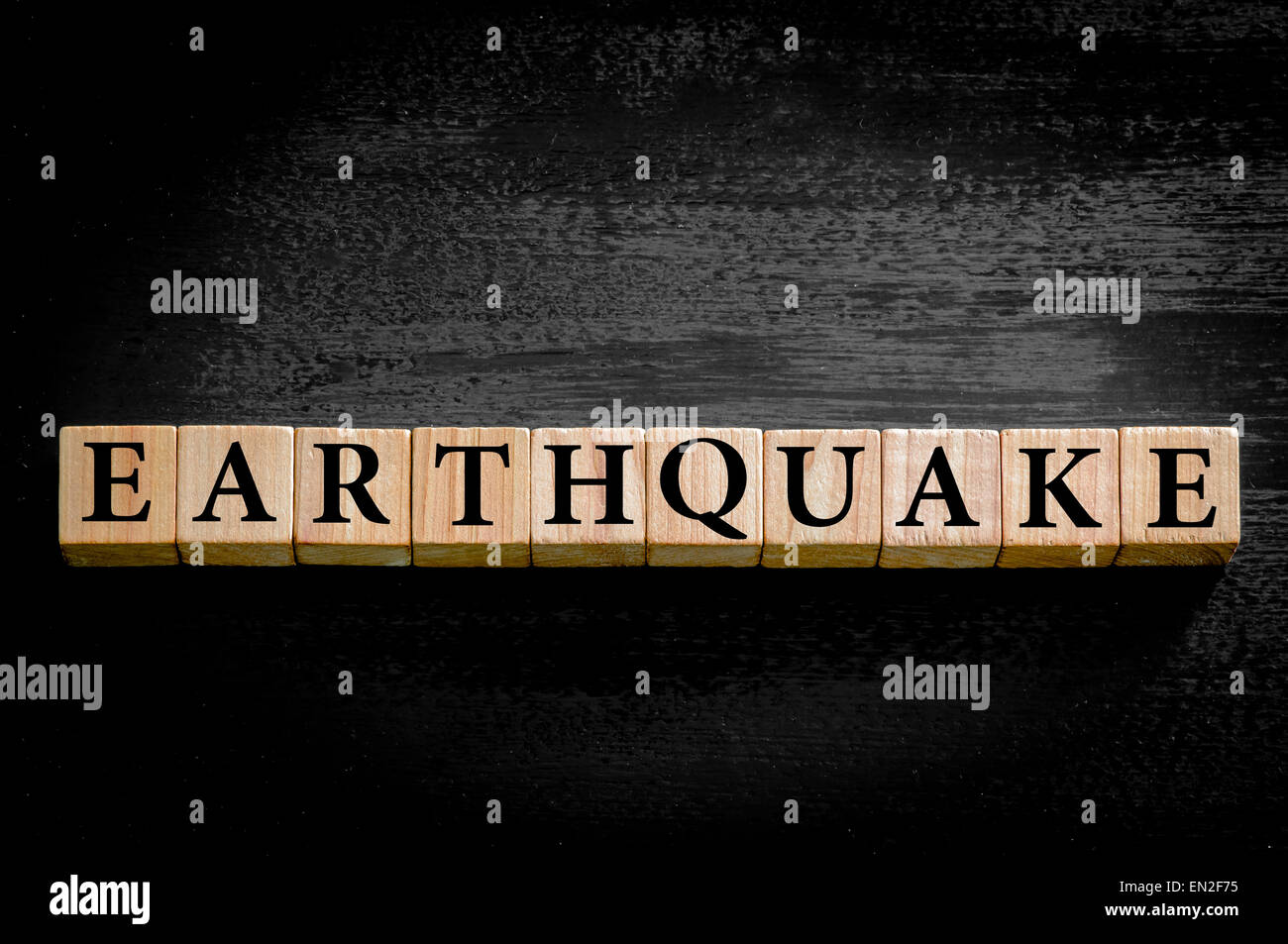 Word EARTHQUAKE. Wooden small cubes with letters isolated on black ...