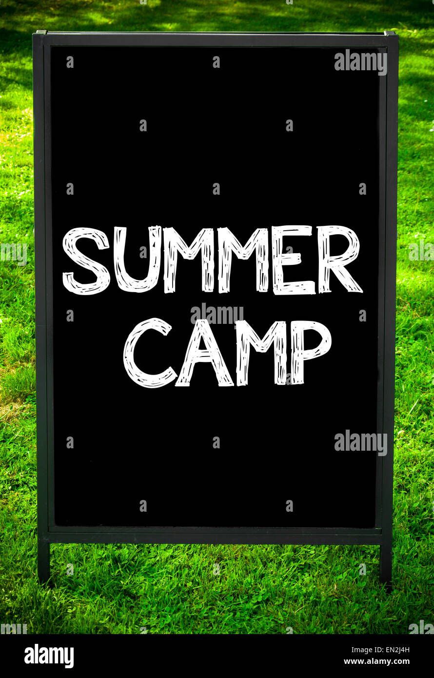SUMMER CAMP message on sidewalk blackboard sign against green grass ...