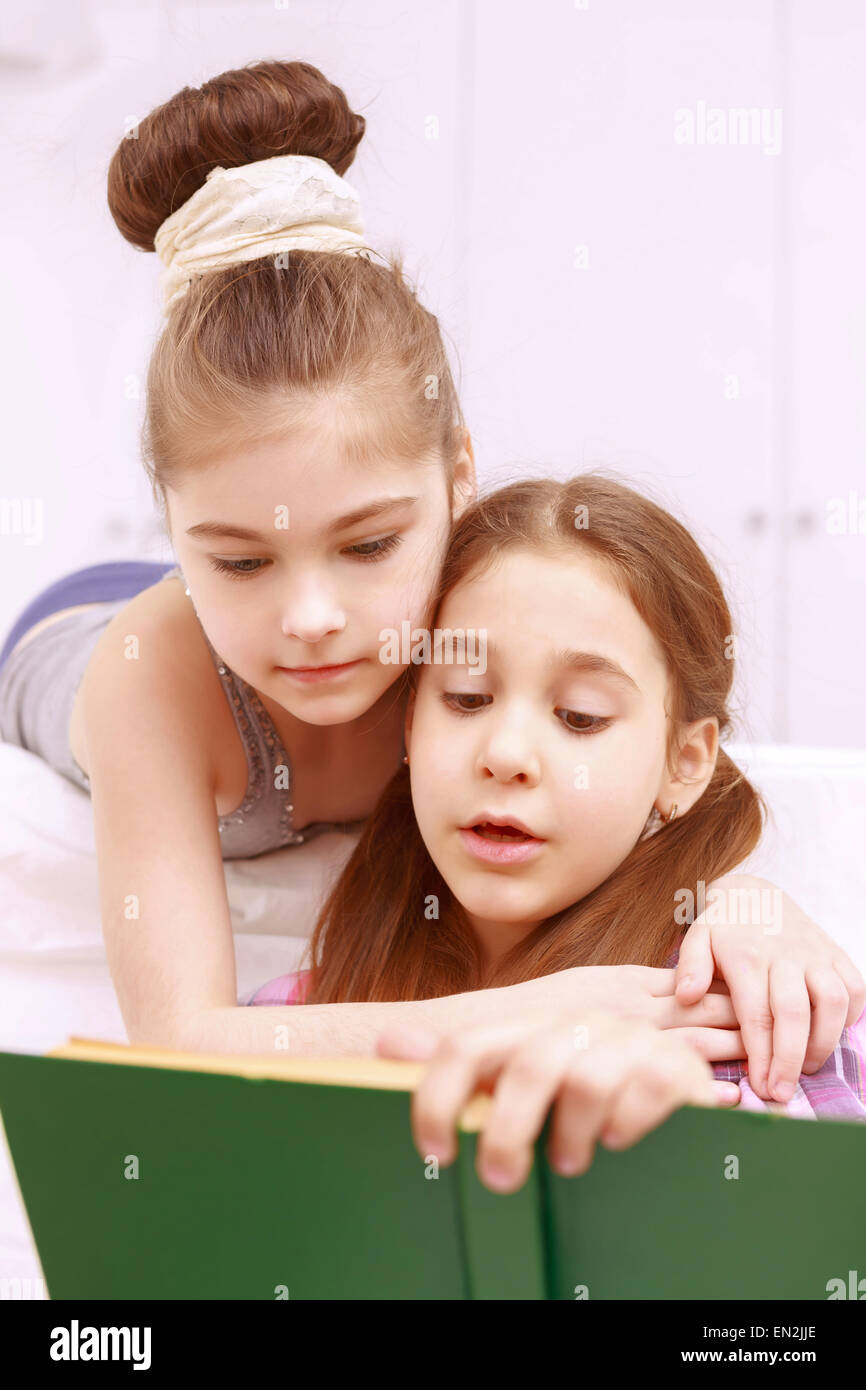 Pair of little girls reading book Stock Photo - Alamy