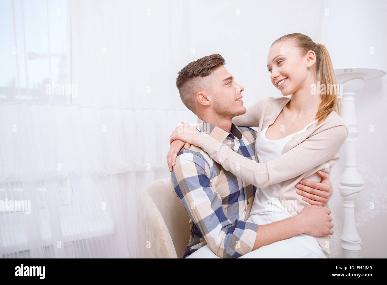 Young lovely couple sitting and hugging Stock Photo - Alamy