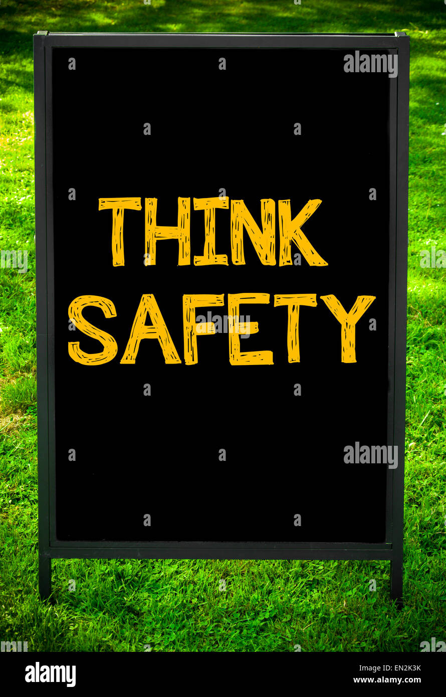 THINK SAFETY message on sidewalk blackboard sign against green grass ...