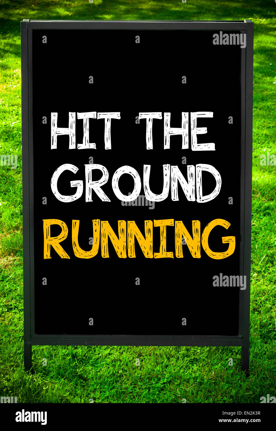 HIT THE GROUND RUNNING message on sidewalk blackboard sign against ...
