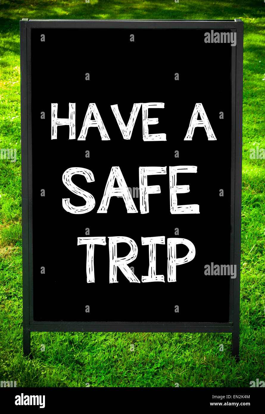 HAVE A SAFE TRIP message on sidewalk blackboard sign against green ...