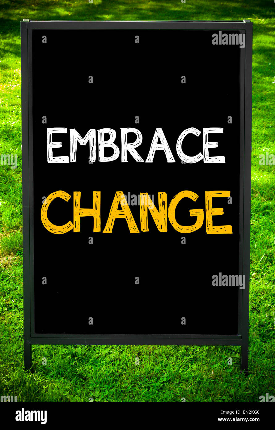 EMBRACE CHANGE message on sidewalk blackboard sign against green grass ...