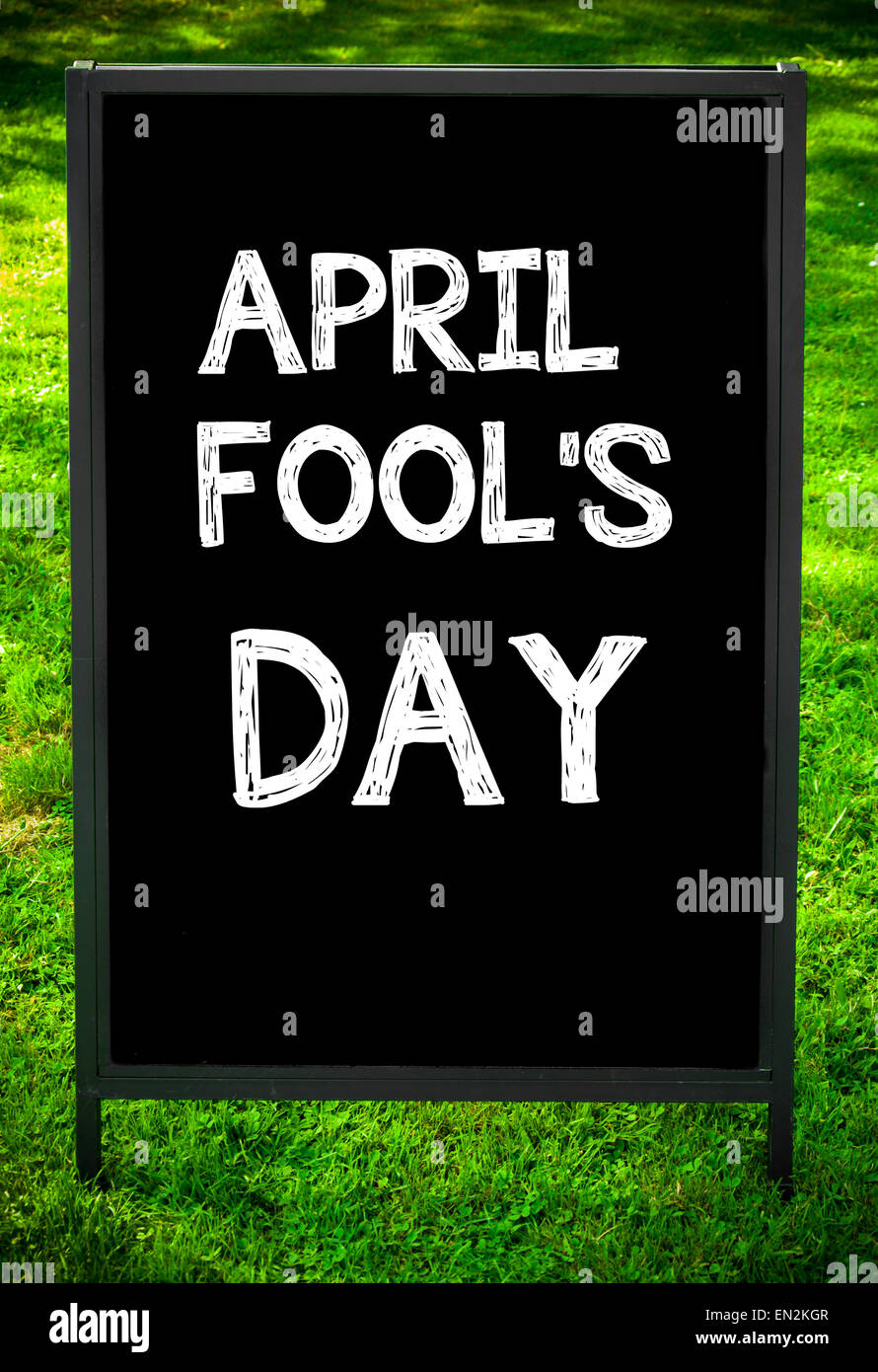 APRIL FOOL'S DAY message on sidewalk blackboard sign against green ...