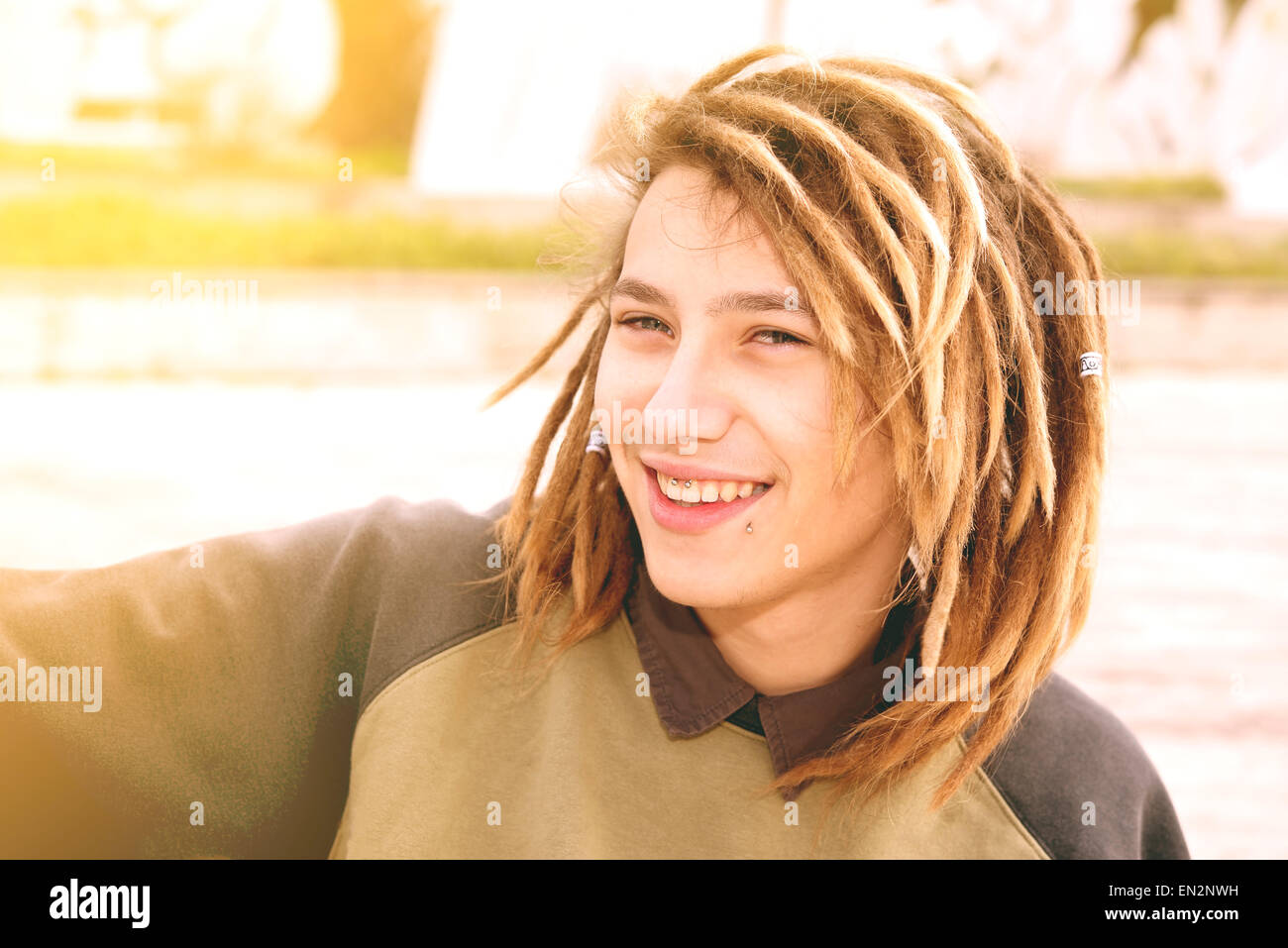 Lifestyle portrait of a young man with rasta hairs warm tones filter ...