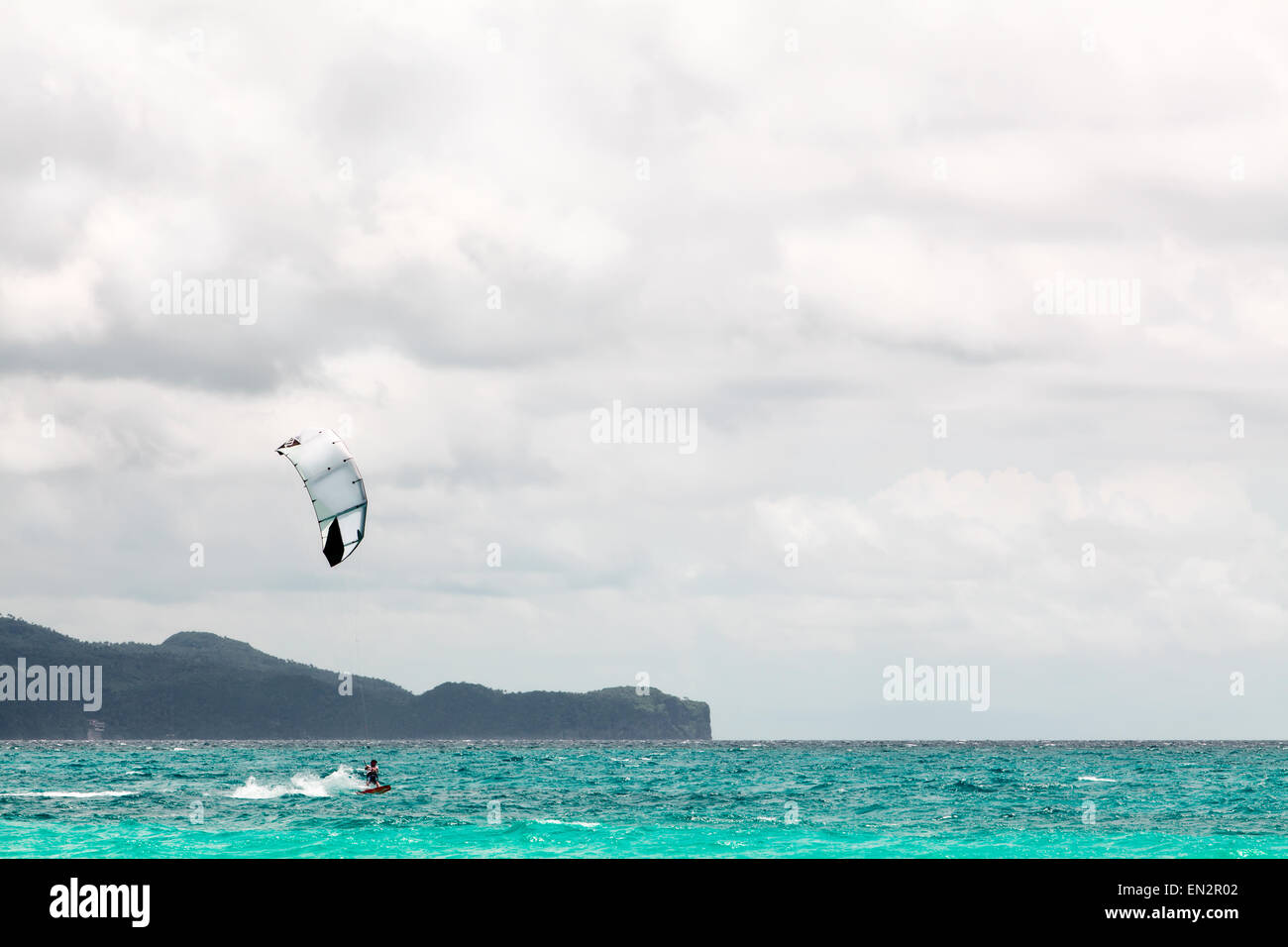Kiter with white kite on horizon of blue tropical sea, big white clouds ...