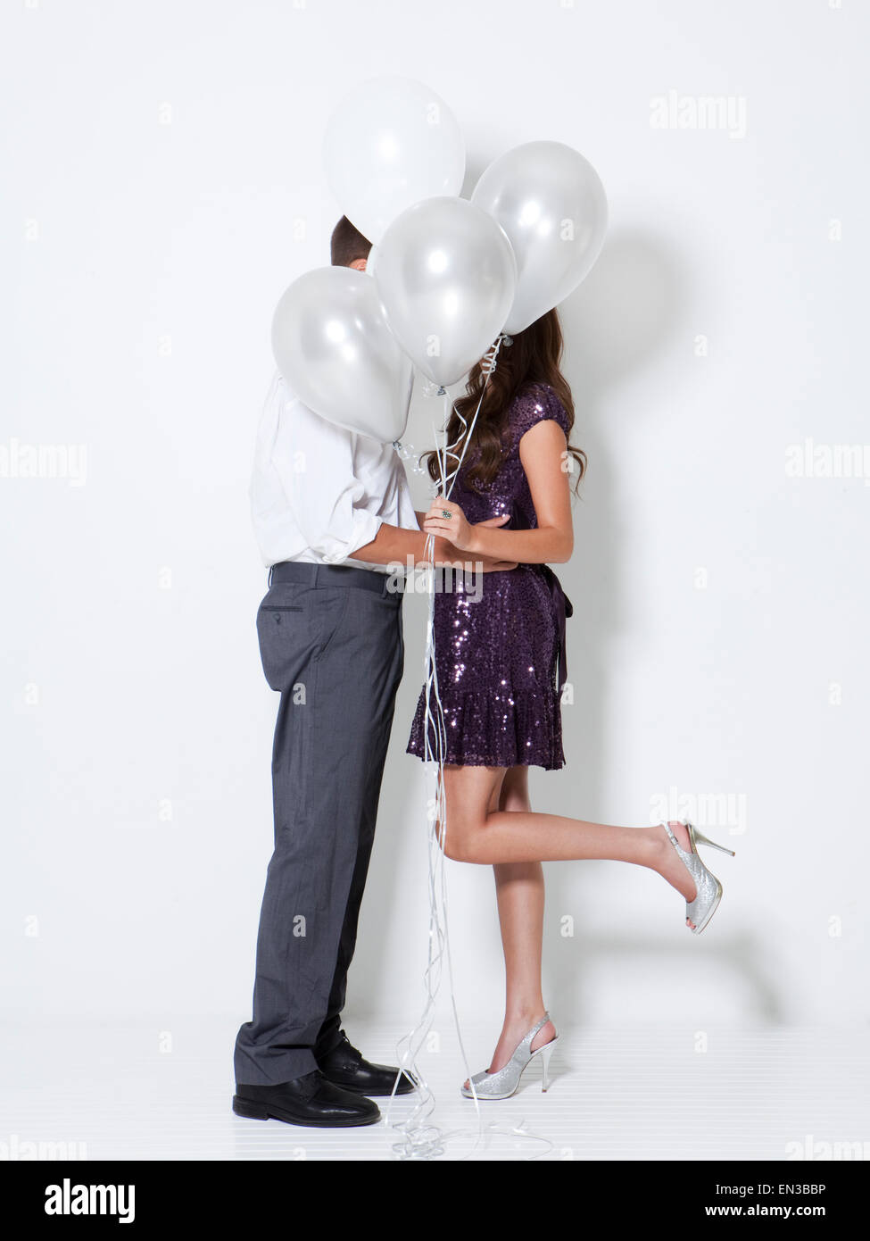 Young couple kissing behind balloons at party Stock Photo - Alamy