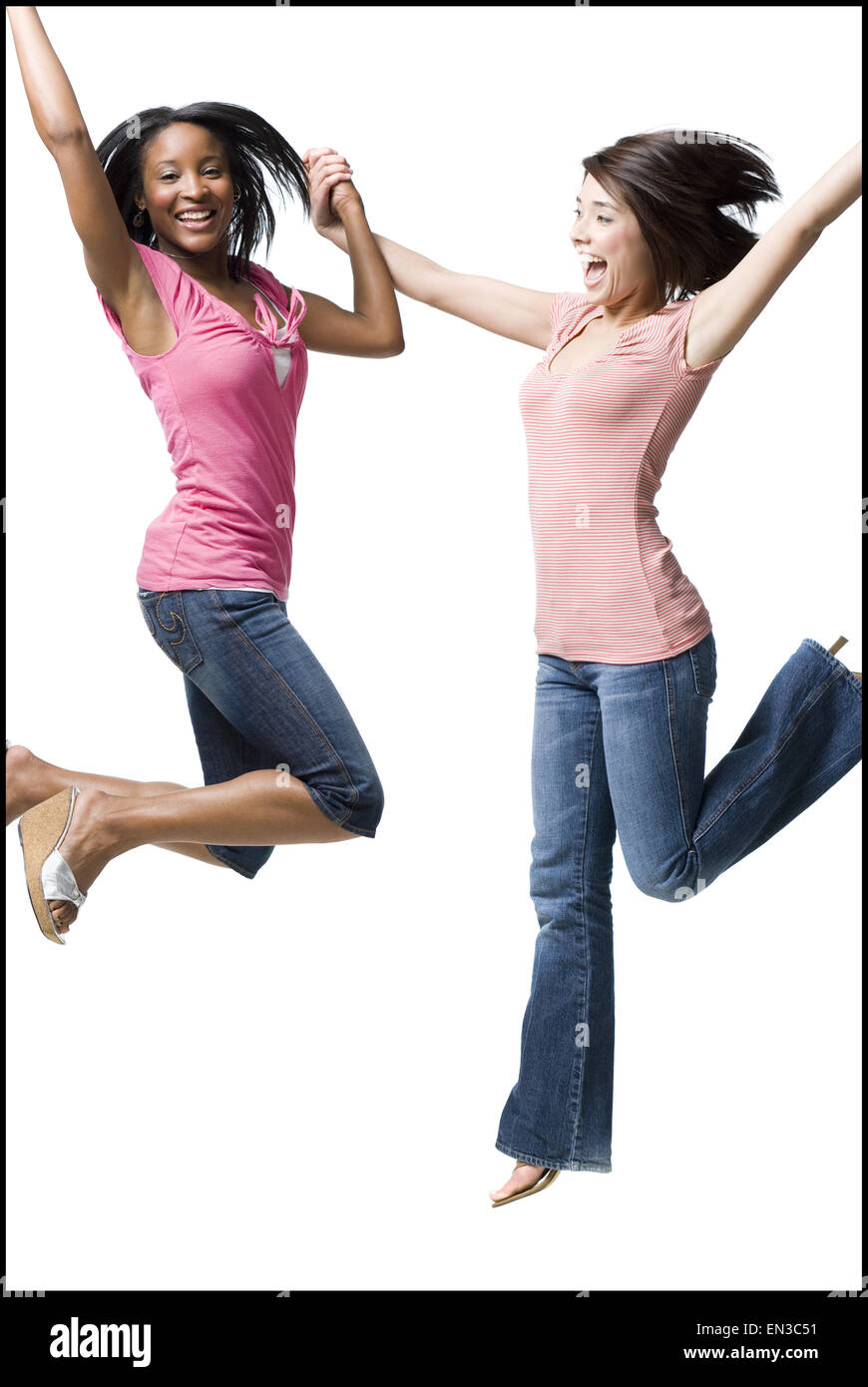 Two women holding hands and jumping Stock Photo - Alamy