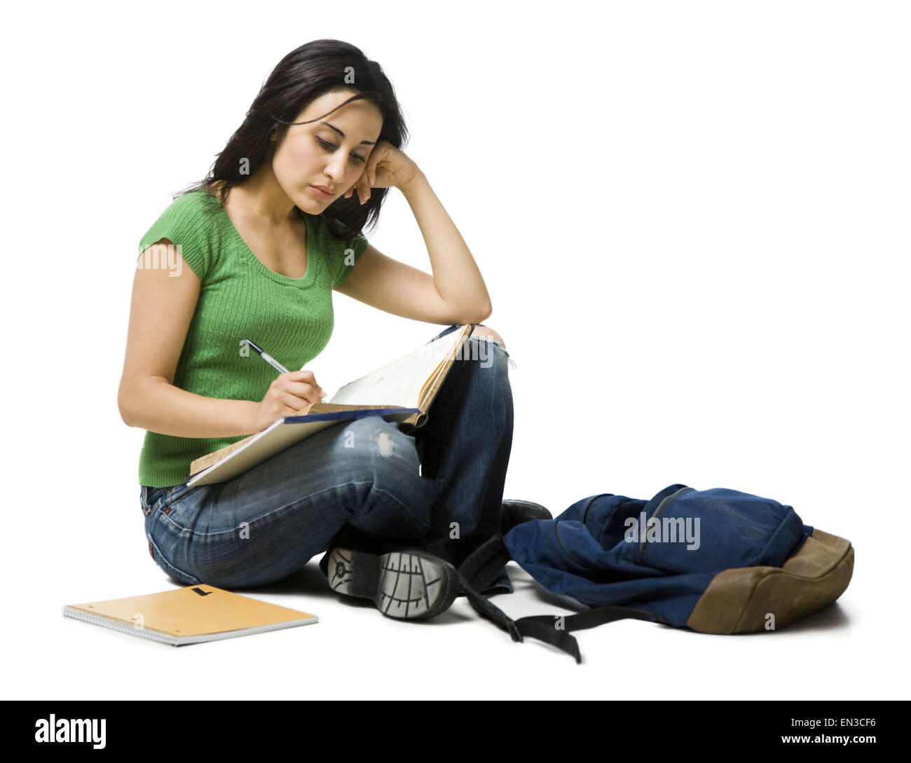 Woman sitting cross legged with backpack doing homework Stock Photo - Alamy