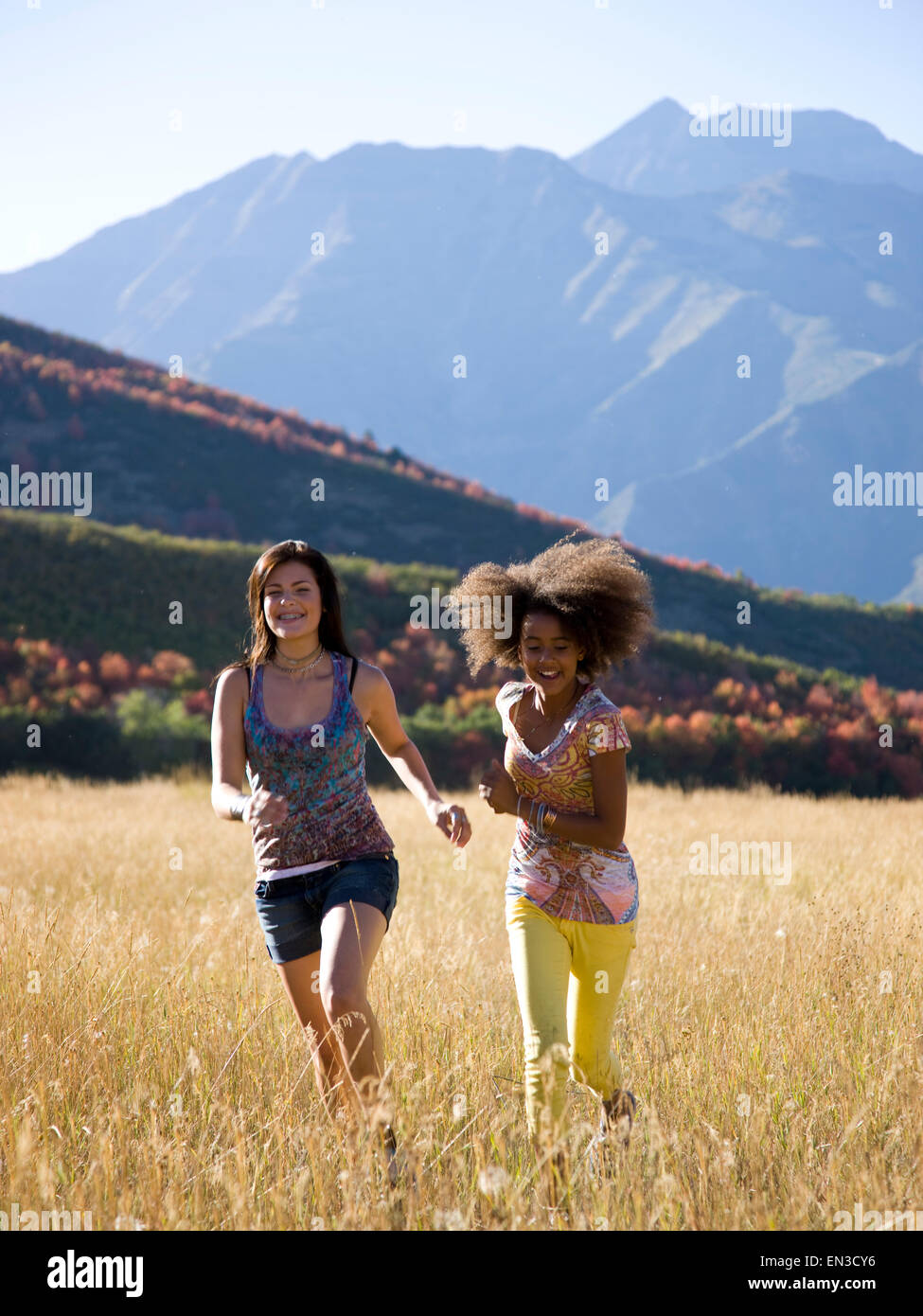 USA, Utah, South Fork, Girls (12-17) running in meadow, mountains in ...