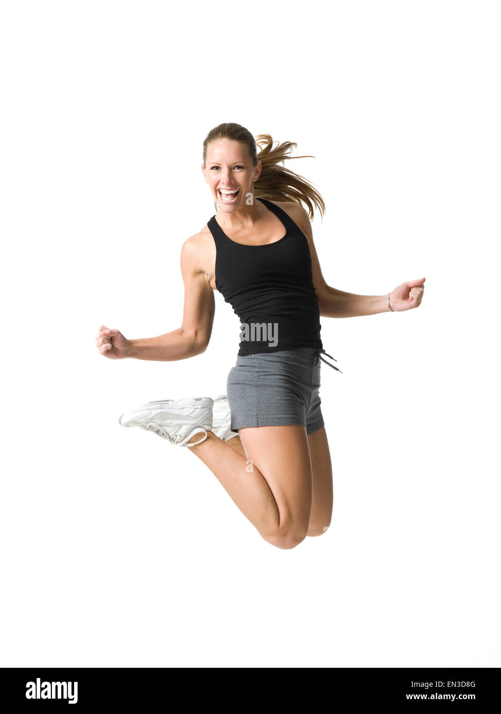 Studio portrait of young woman jumping, smiling Stock Photo - Alamy