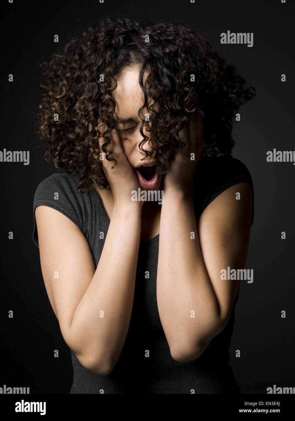 Woman with mouth open and closed eyes with hands on face Stock Photo ...