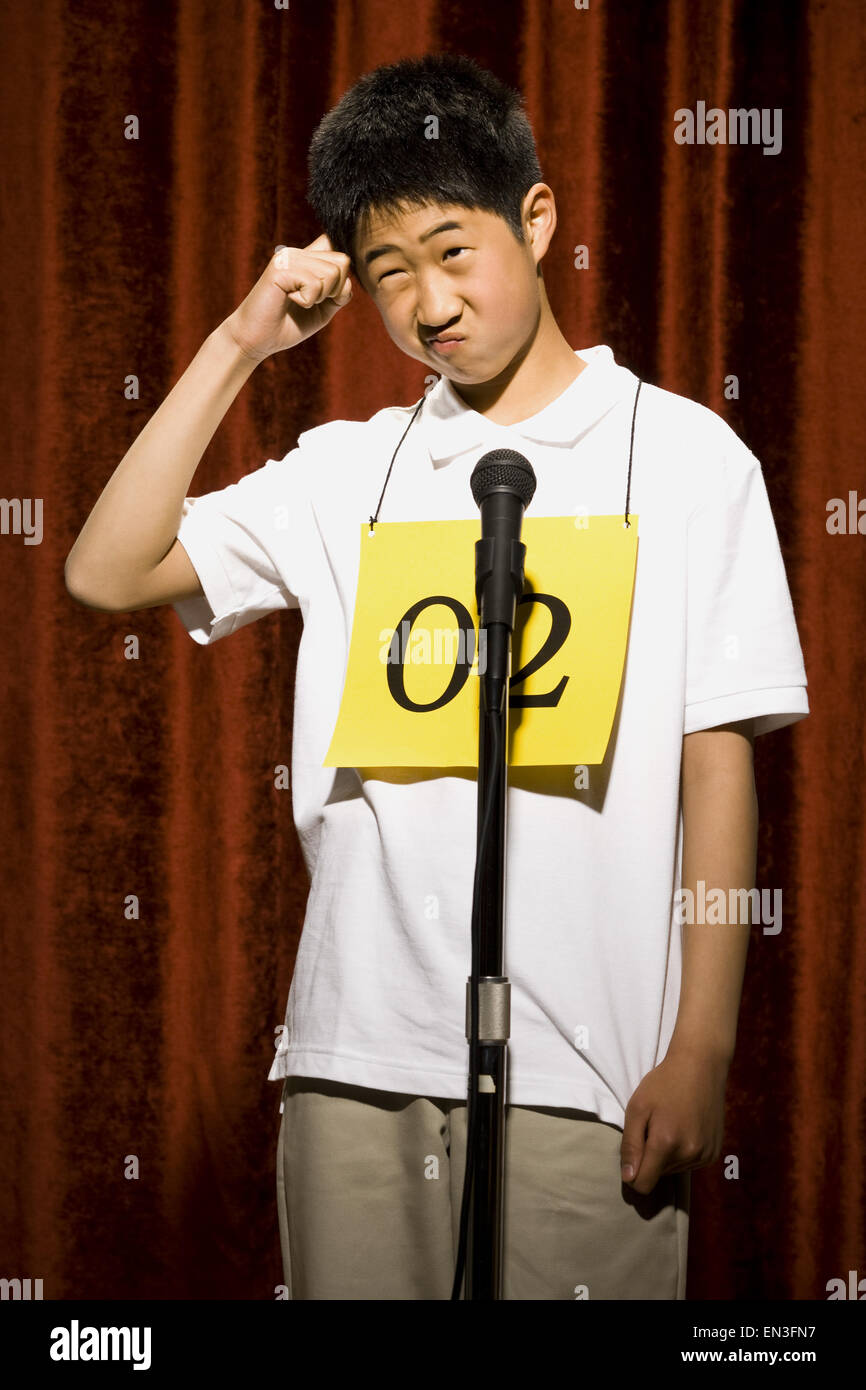 Boy at microphone with number around neck scratching head Stock Photo ...
