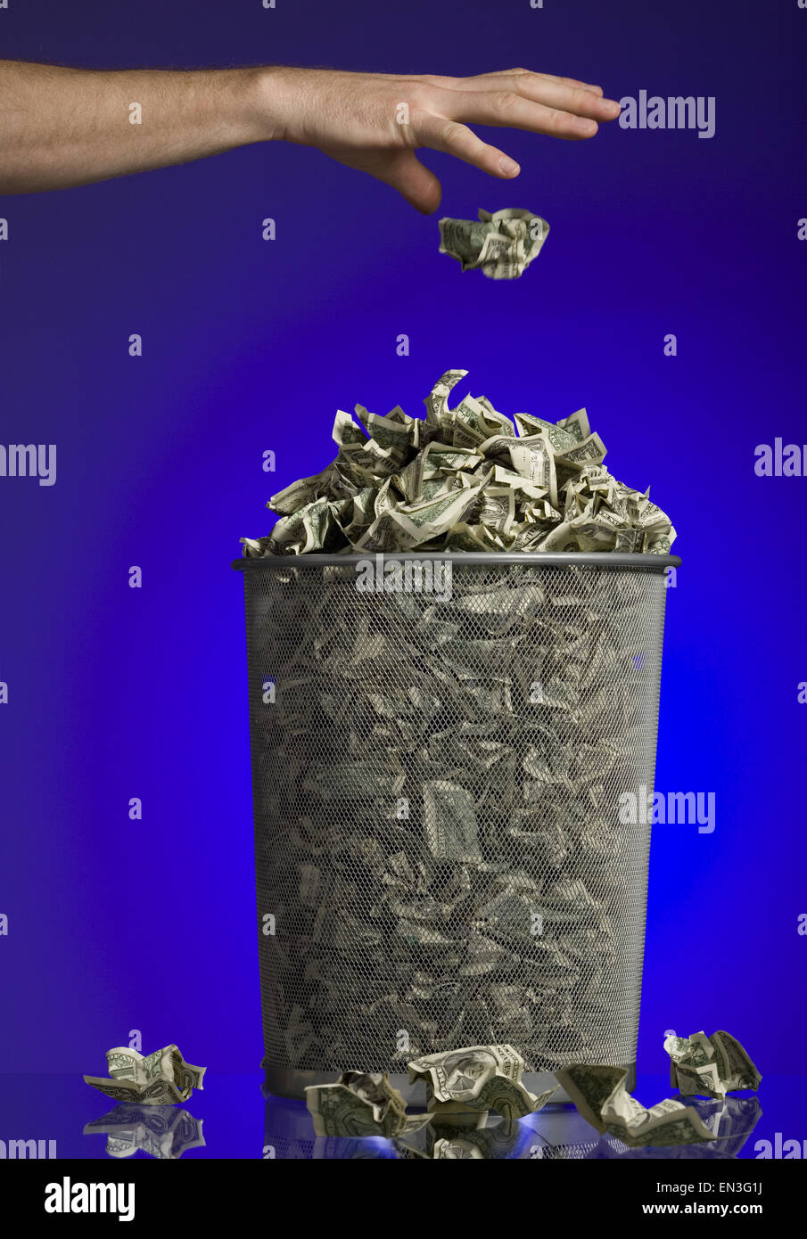 Person throwing crumpled money into waste paper basket Stock Photo - Alamy