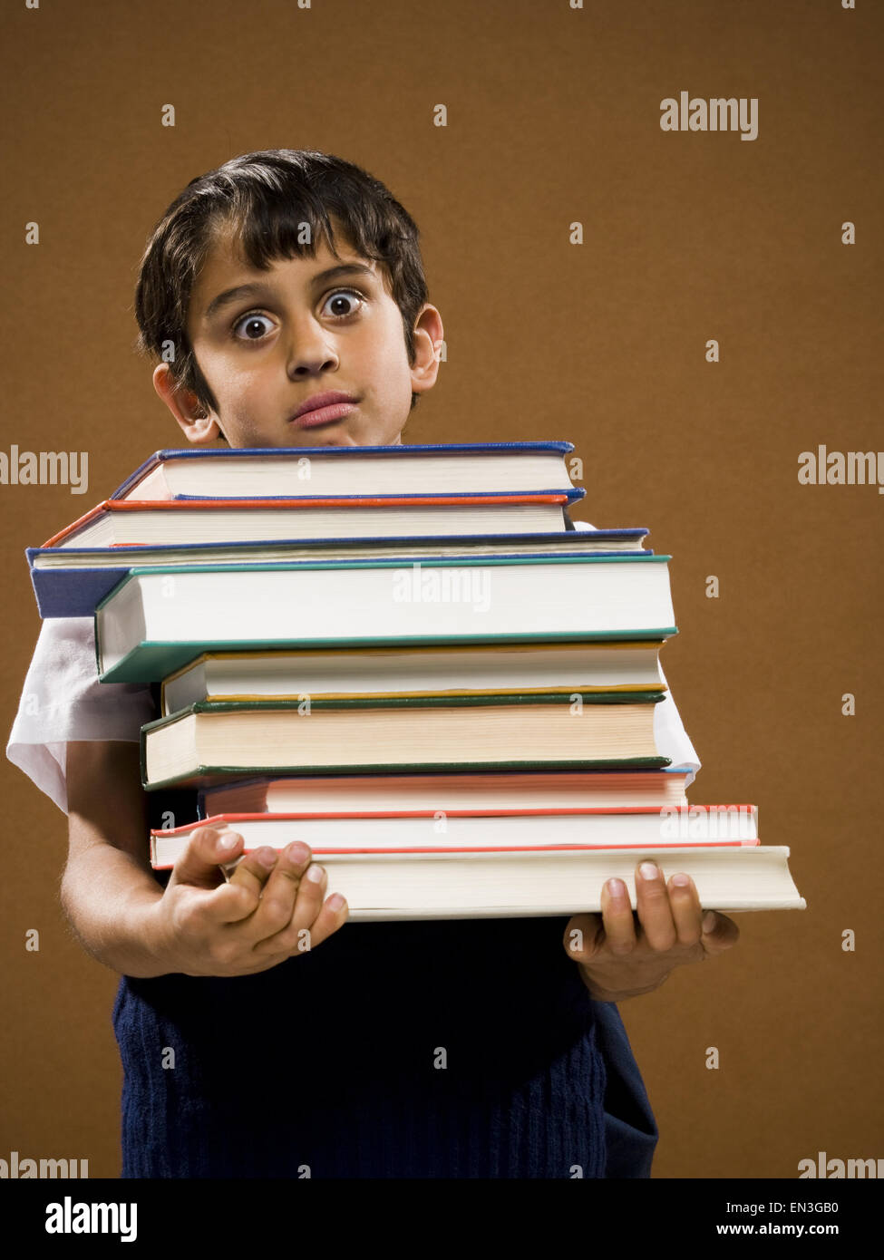 Boy holding pile of textbooks Stock Photo - Alamy
