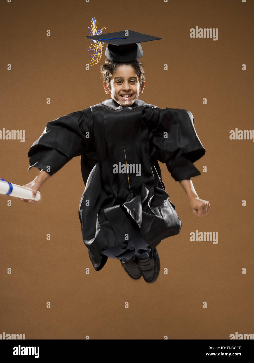 Boy graduate with mortar board and diploma leaping and smiling Stock ...