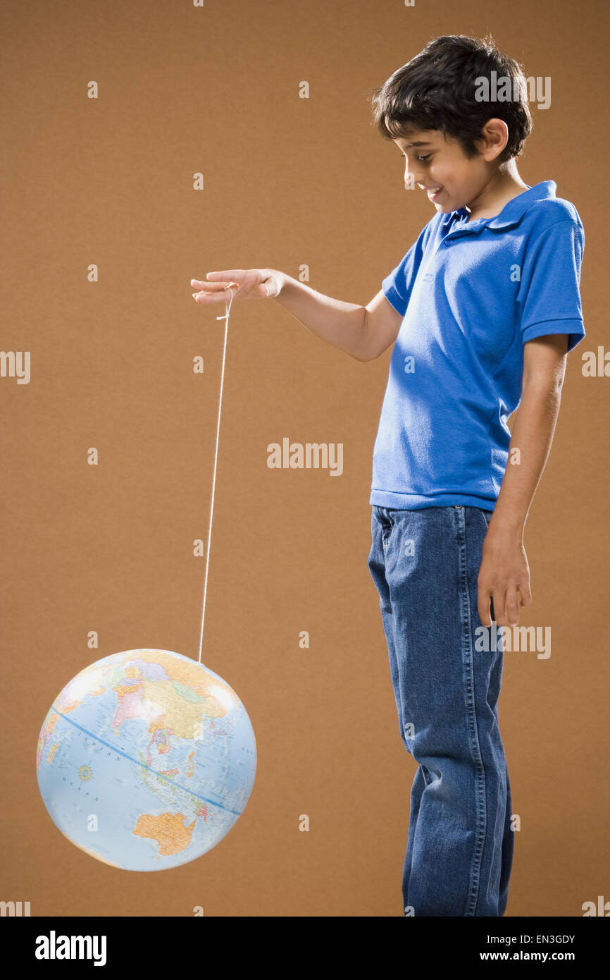 Boy holding string with globe attached smiling Stock Photo - Alamy