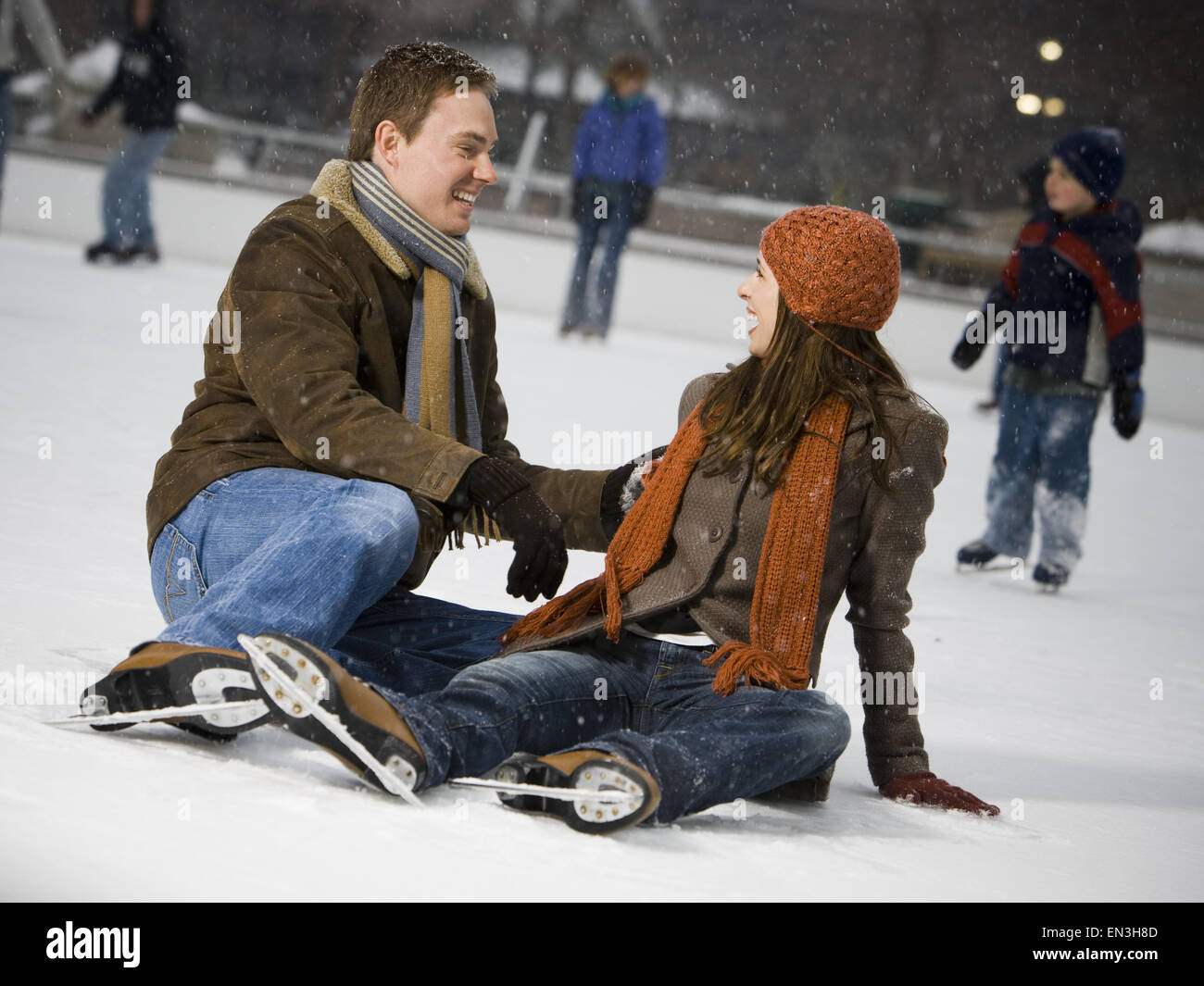Couple falling while ice skating Stock Photo - Alamy