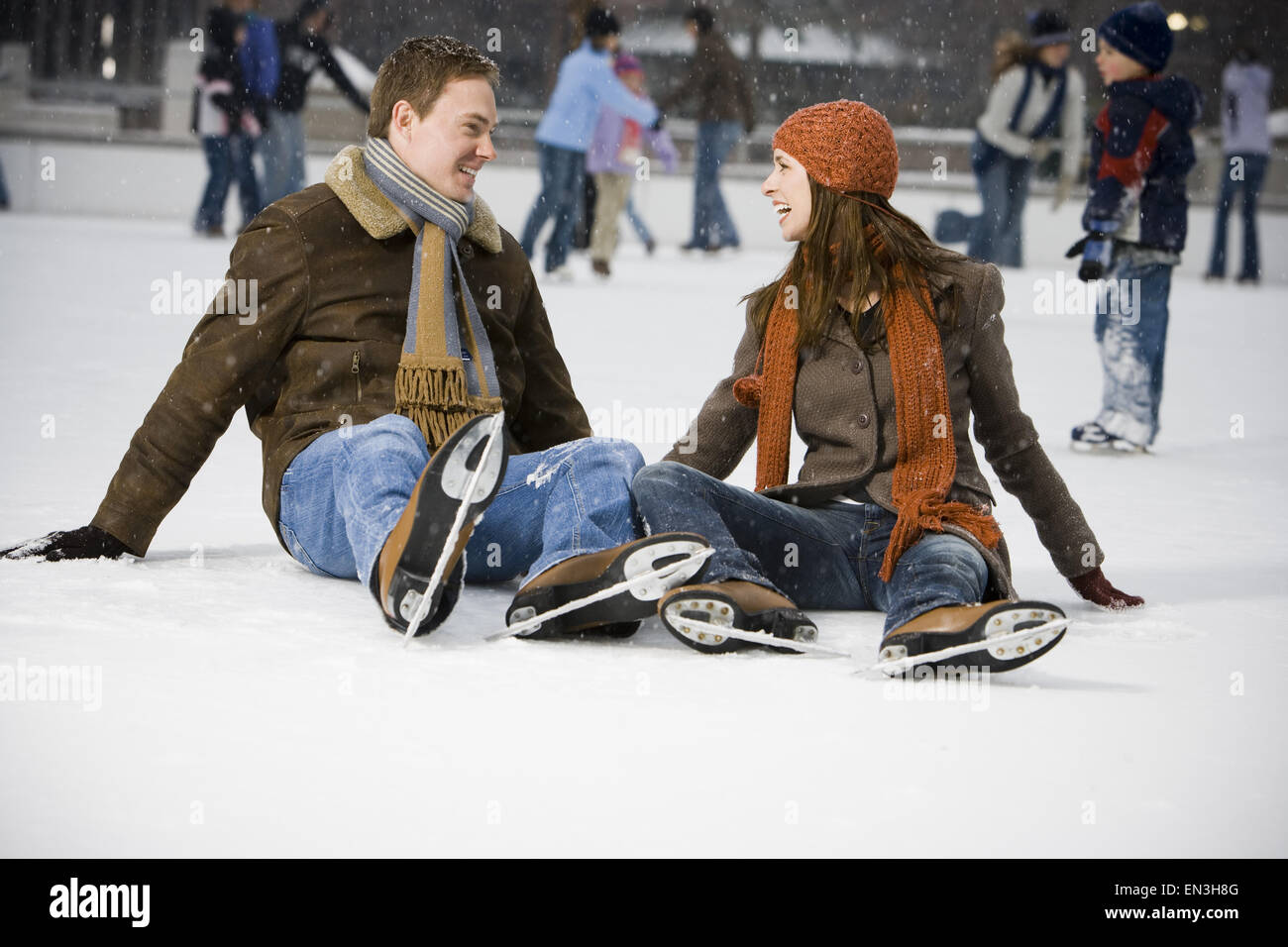 Couple falling while ice skating Stock Photo - Alamy