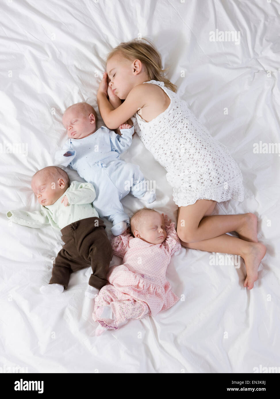 big sister lying with newborn triplets Stock Photo - Alamy