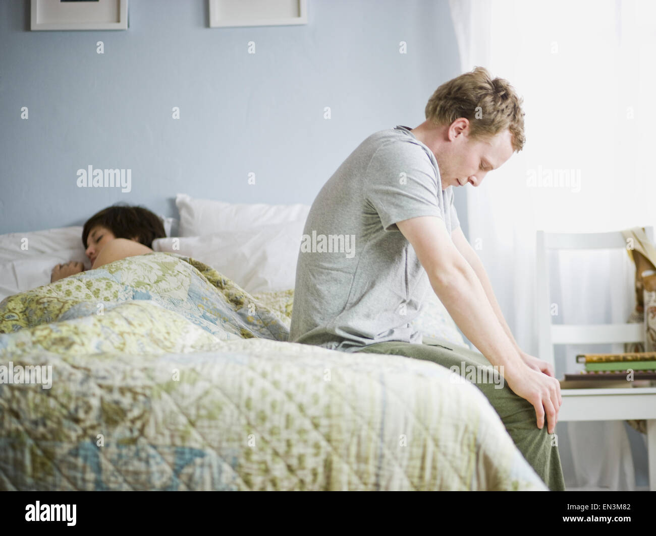 man sitting on the edge of a bed Stock Photo - Alamy