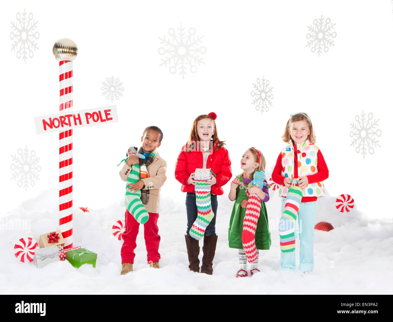 Group of kids (18-23months, 4-5,6-7) standing next to North Pole sign ...