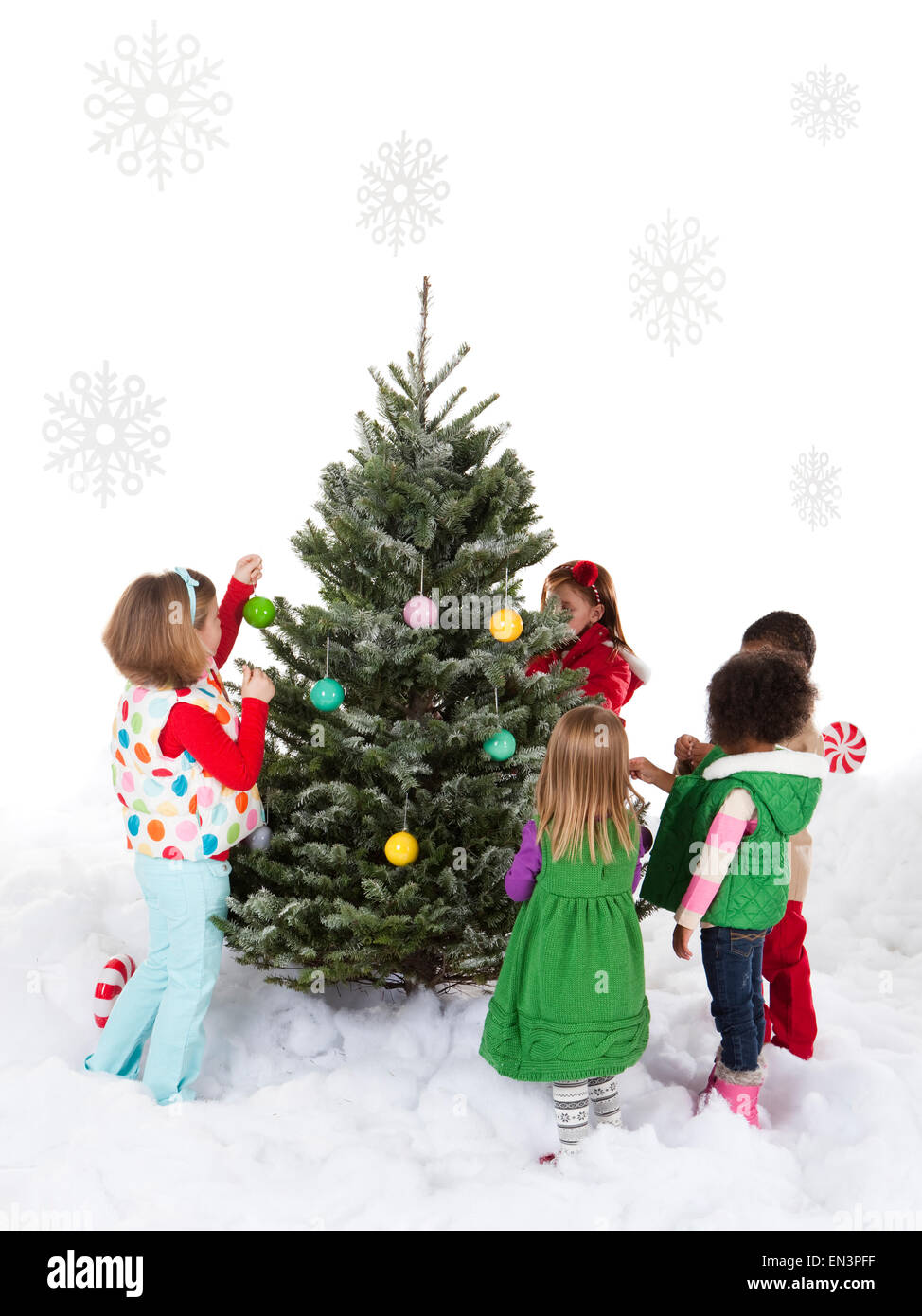 Group of kids (18-23months, 4-5,6-7) standing around christmas tree ...