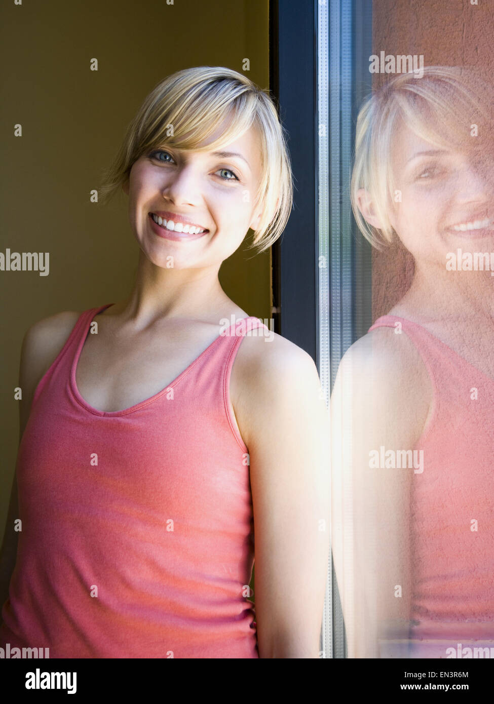 Woman smiling and leaning with reflection Stock Photo - Alamy
