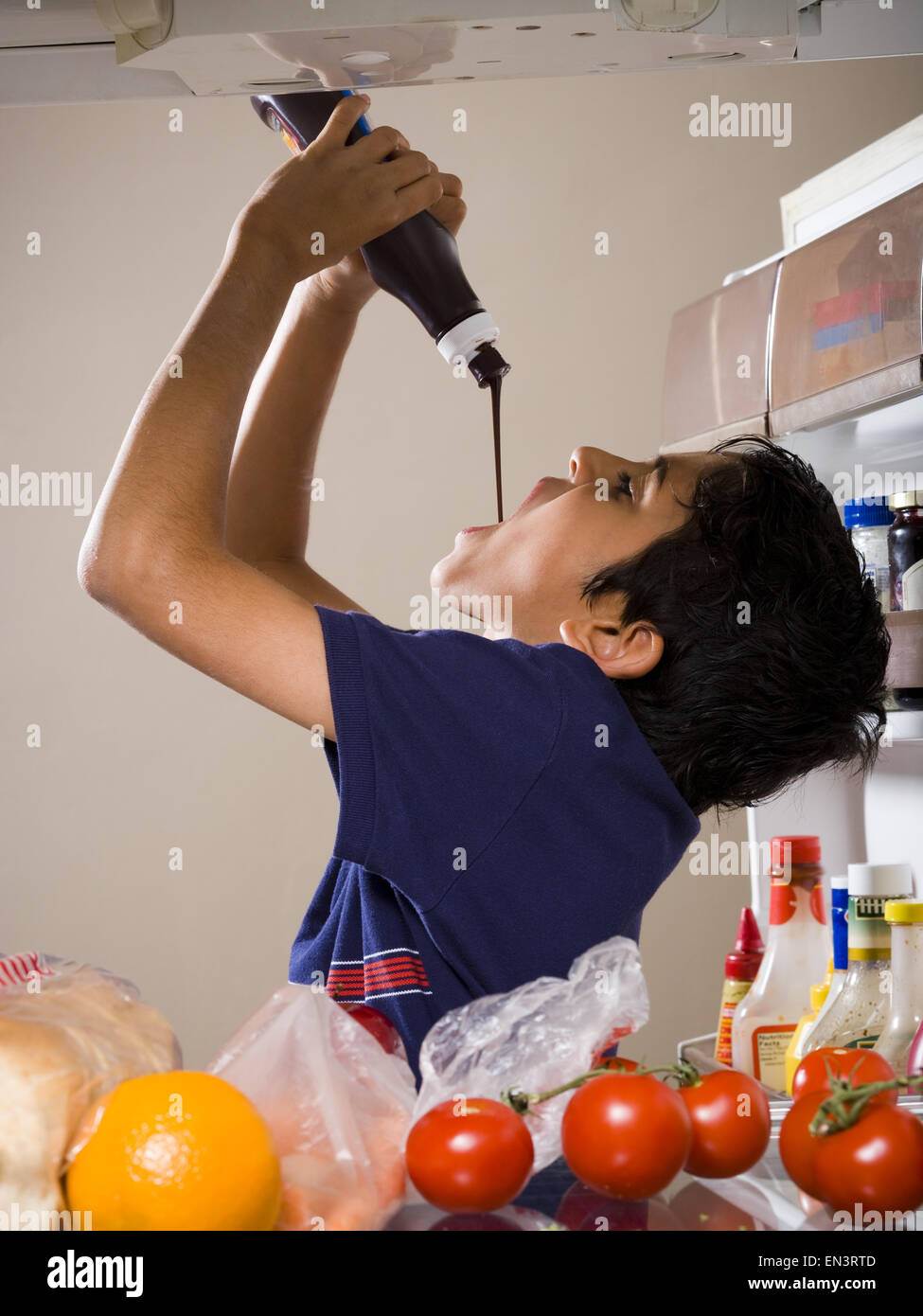 Boy drinking chocolate syrup from bottle in refrigerator Stock Photo ...
